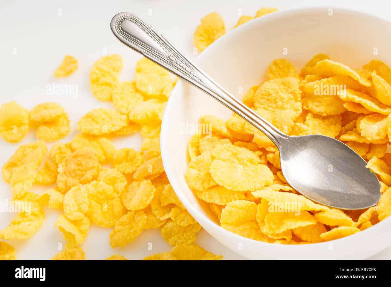 Yellow corn flakes in white bowl with spoon Stock Photo - Alamy