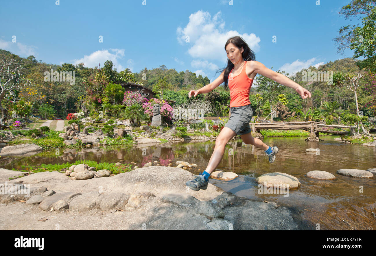 Woman jumping on kobbel stones over a small pond Stock Photo - Alamy