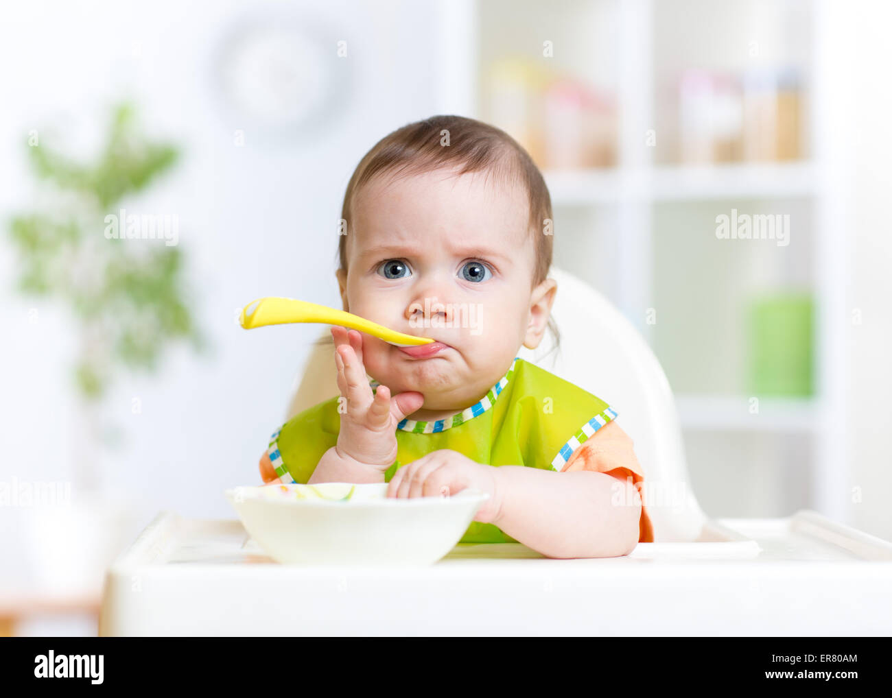 funny baby girl eating food on kitchen Stock Photo - Alamy