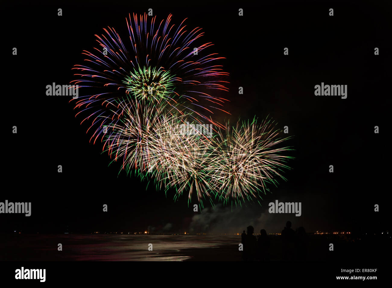 People admiring pyrotechnic show from the beach fireworks reflecting in ...