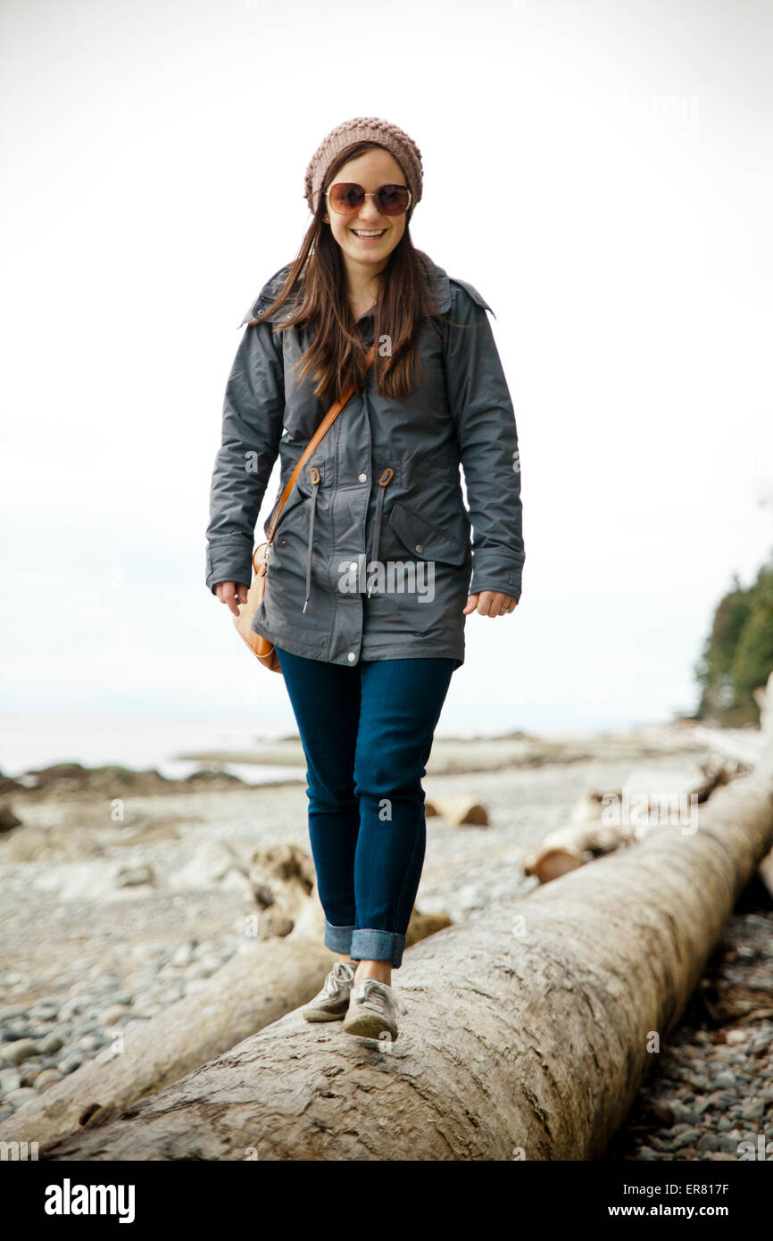 A young woman walks on a long log at the beach in BC, Canada Stock ...