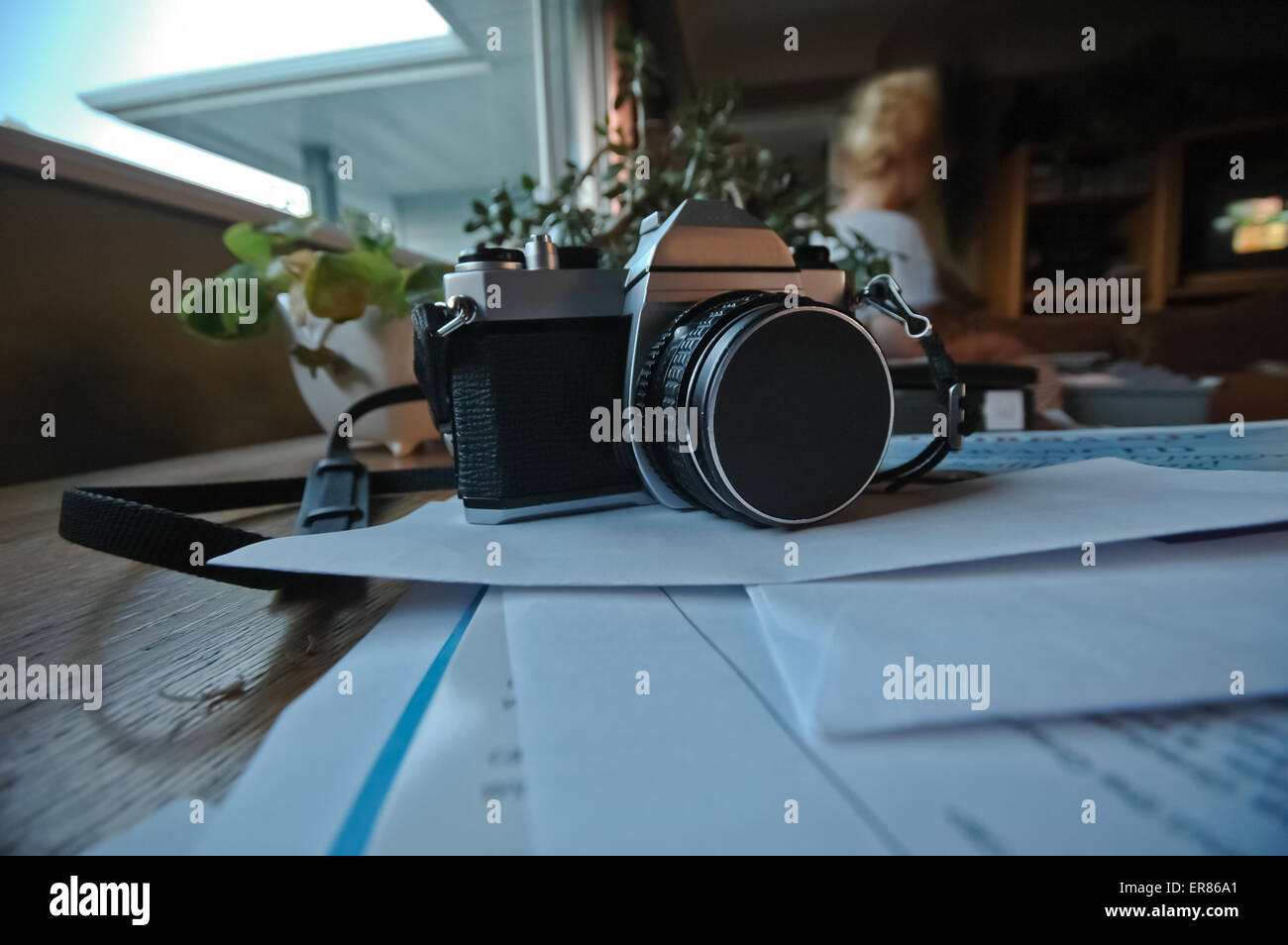 Vintage silver film SLR camera placed on top of pile of documents in a ...