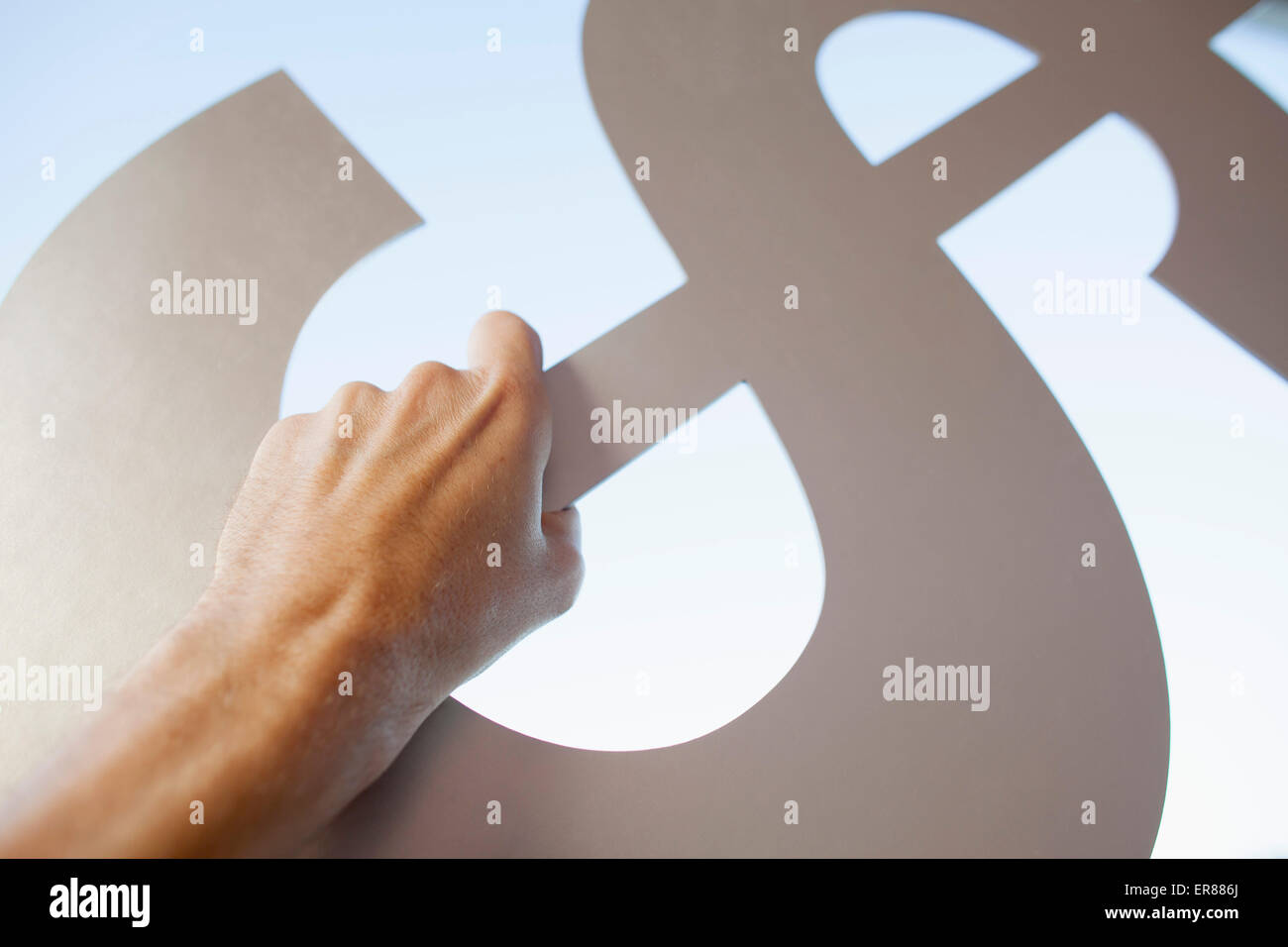 Cropped image of hand holding dollar sign against sky Stock Photo - Alamy