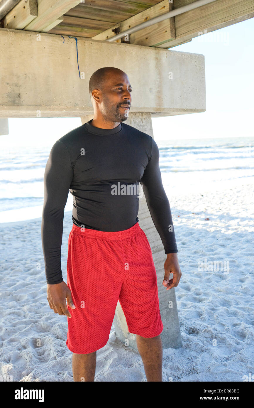 Man standing under a pier on the beach Stock Photo - Alamy