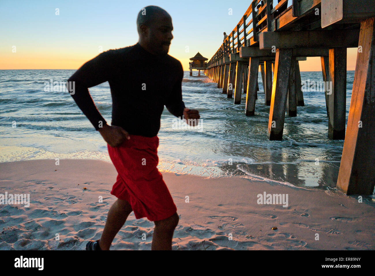 Man running on the beach at sunset Stock Photo - Alamy