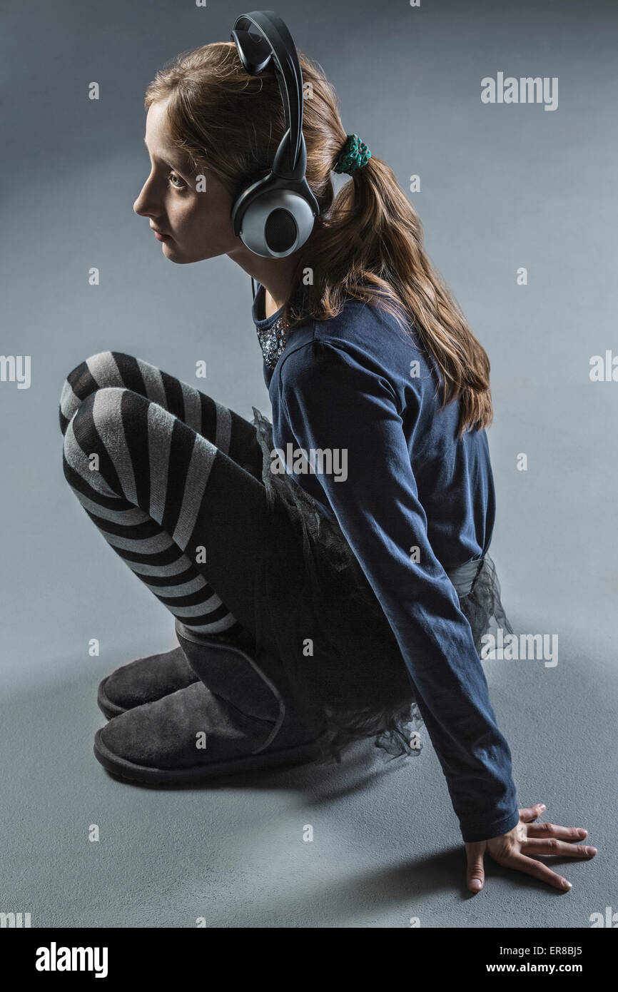 Full length side view of girl crouching while listening music through ...