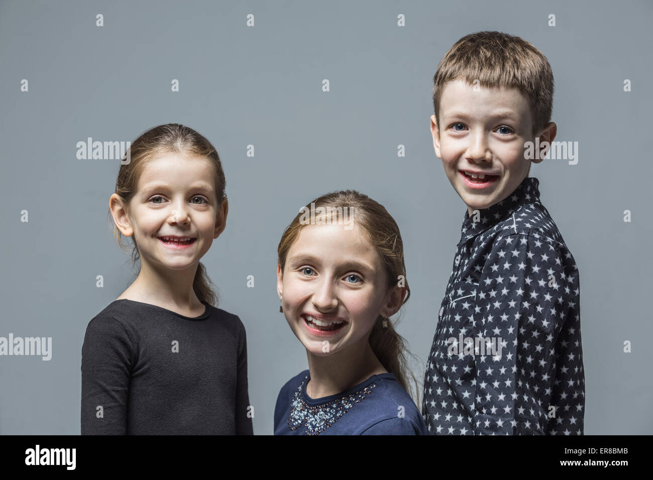 Portrait of smiling brother with sisters over gray background Stock ...