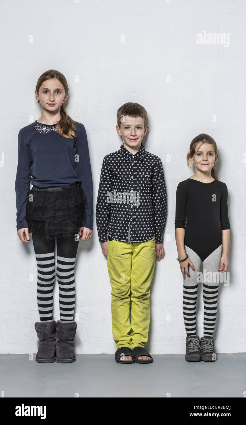 Full Length Portrait Of Smiling Brother With Sisters Standing Side By