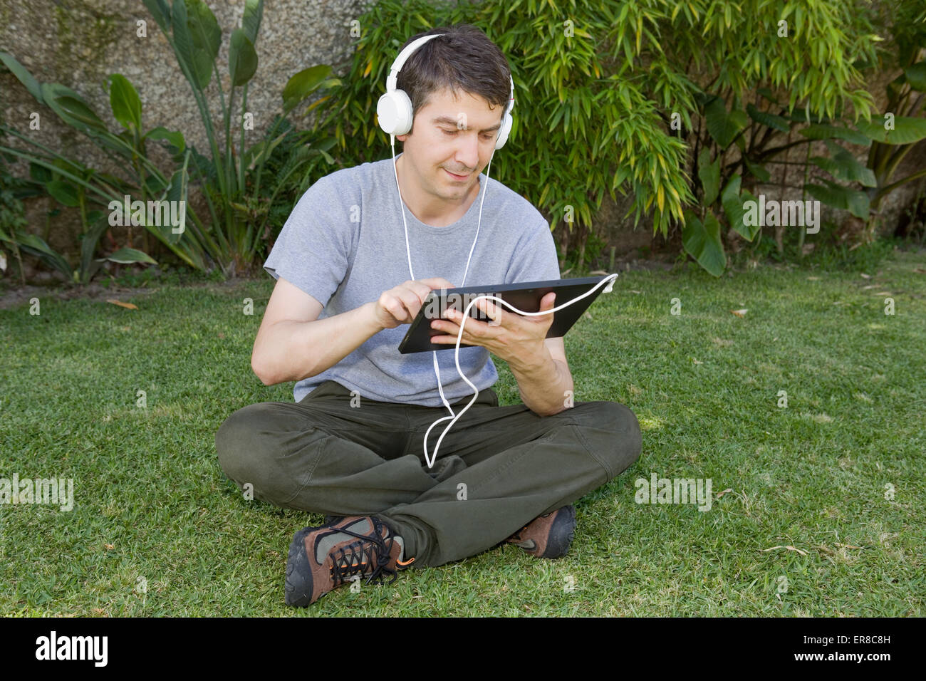 young man holding a tablet with headphones, outdoor Stock Photo - Alamy