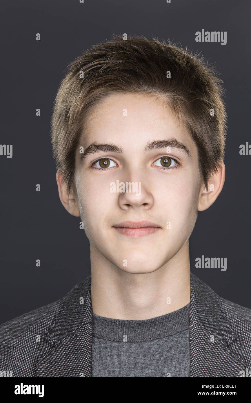 Close-up portrait of confident teenage boy over gray background Stock ...