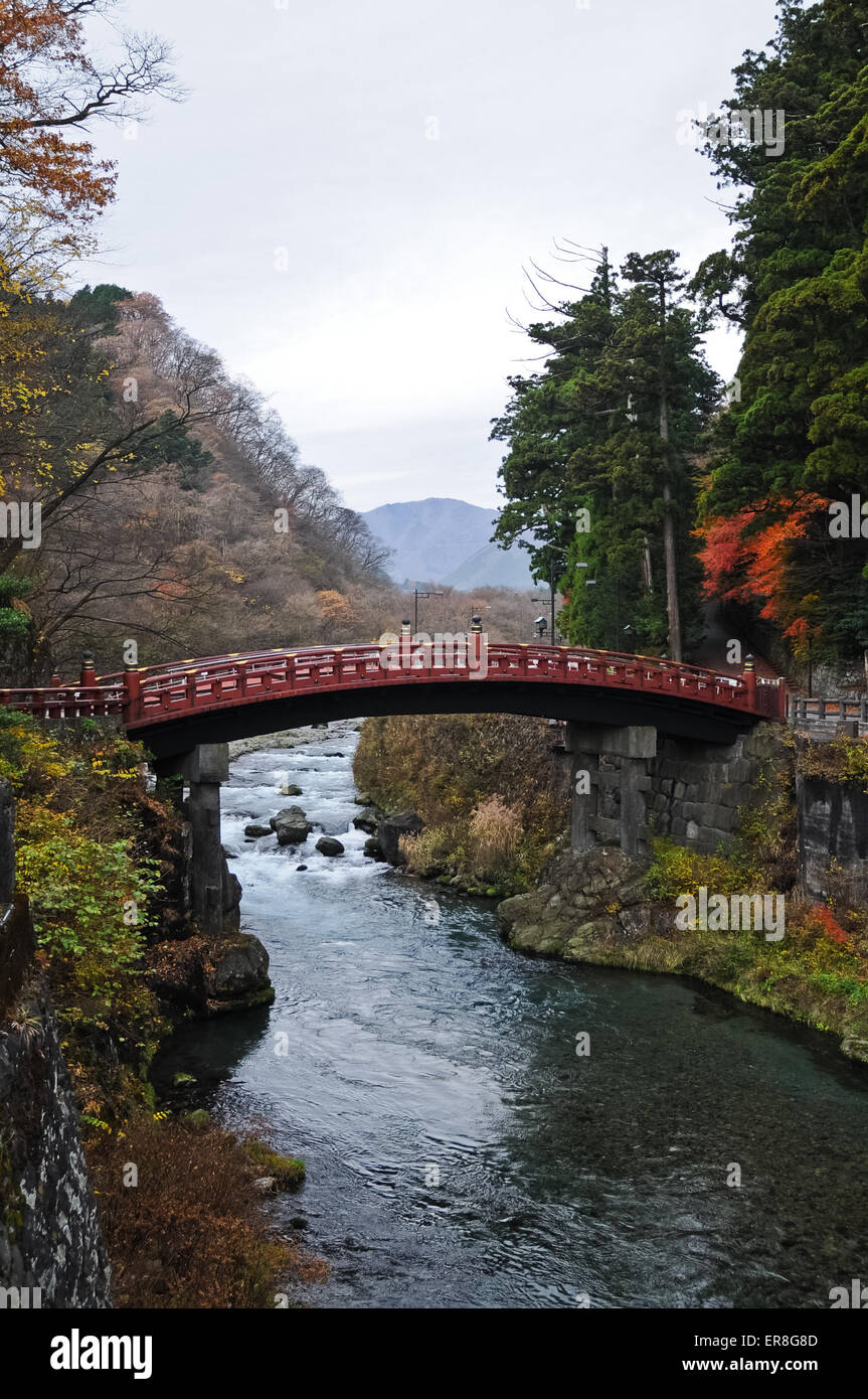 Ancient Japanese red arc bridge crossing creek surrounded by Autumn ...