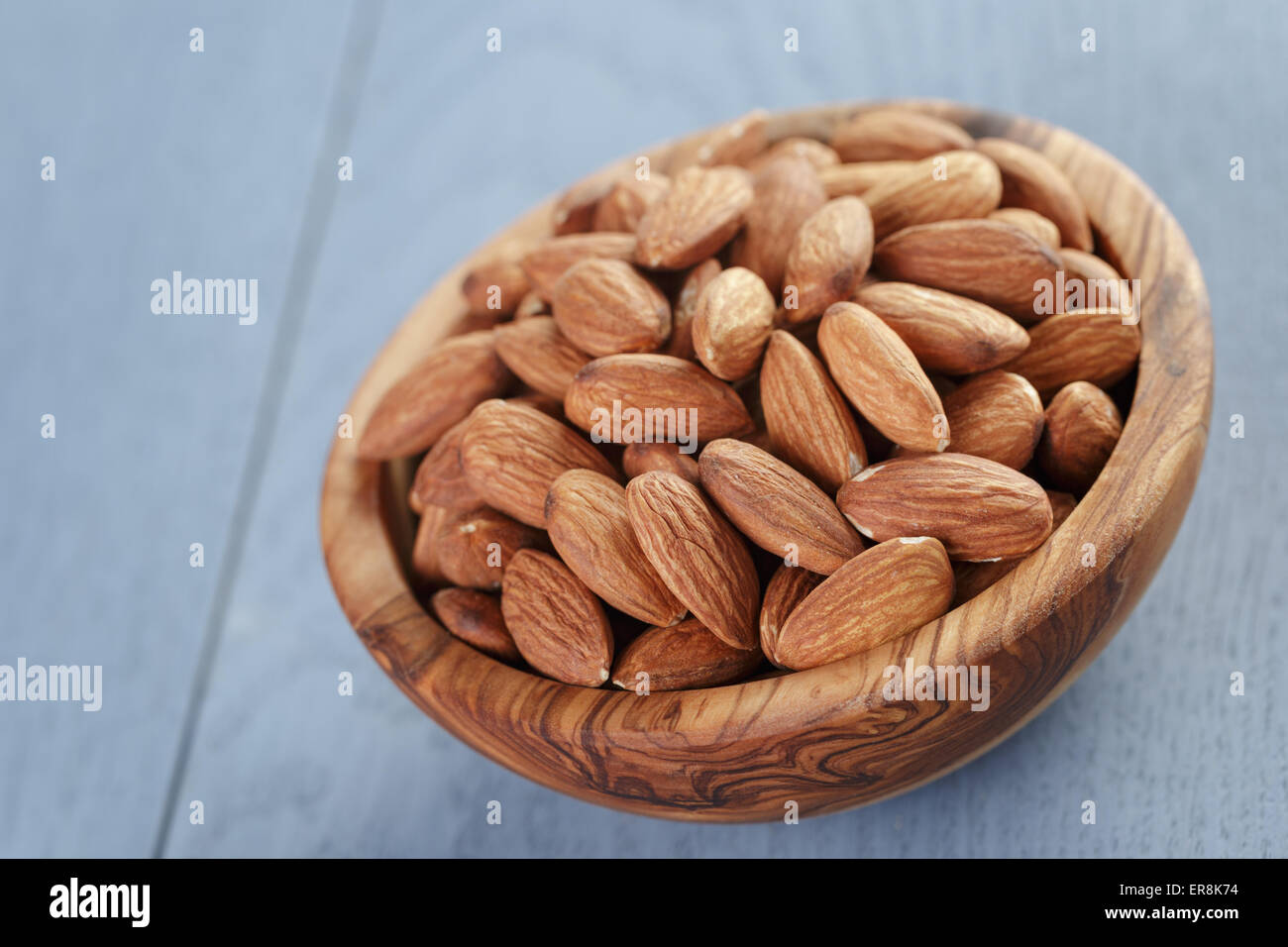 roasted almonds in bowl on blue wooden table Stock Photo - Alamy