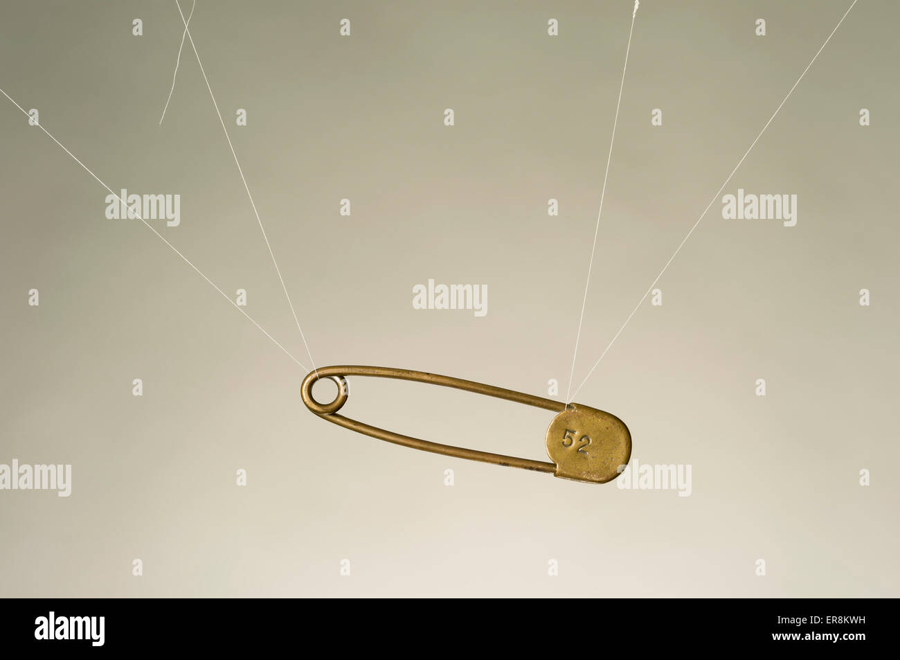 Strings tied to safety pin hanging against white background Stock Photo ...