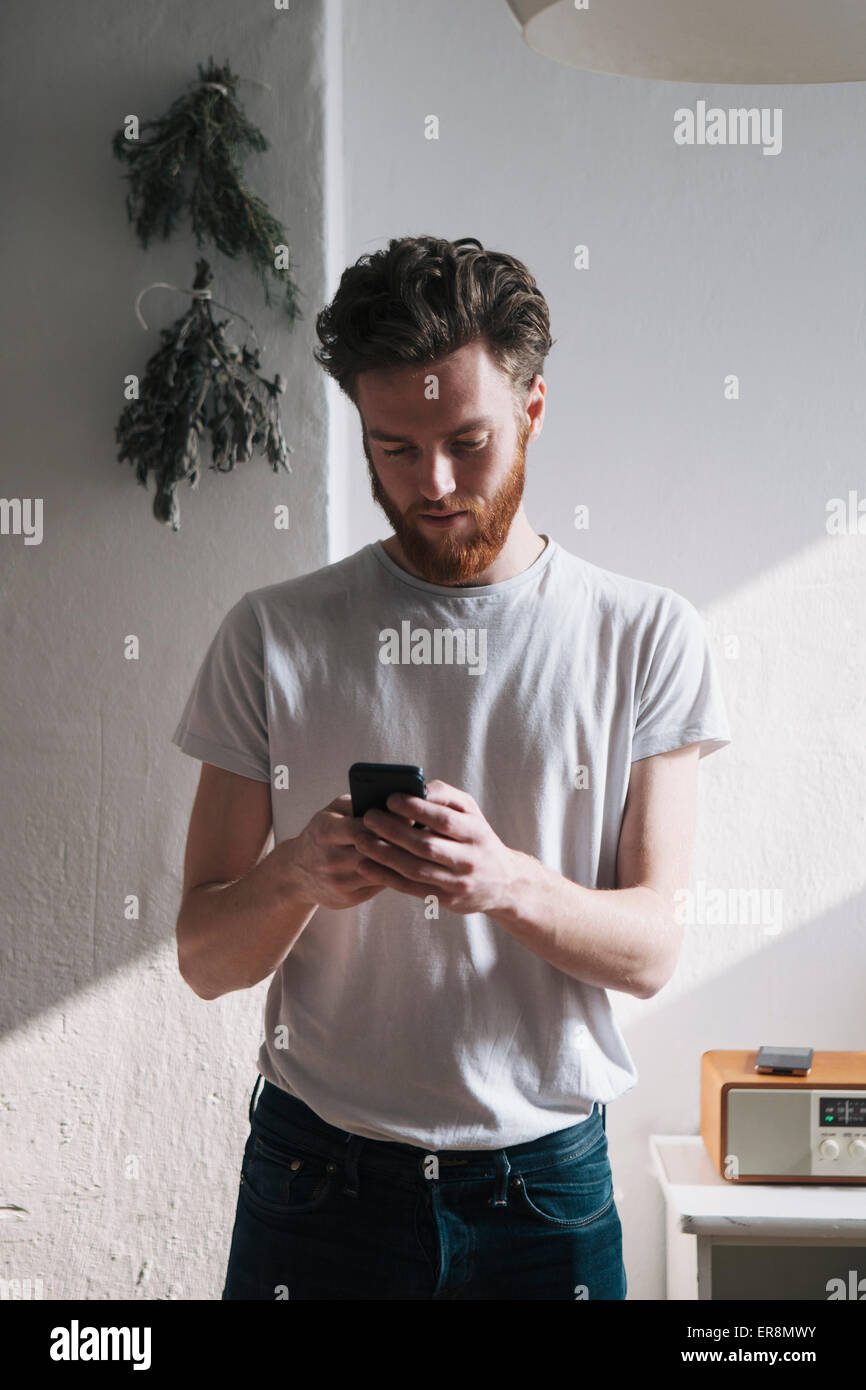 Young man using mobile phone at home Stock Photo - Alamy