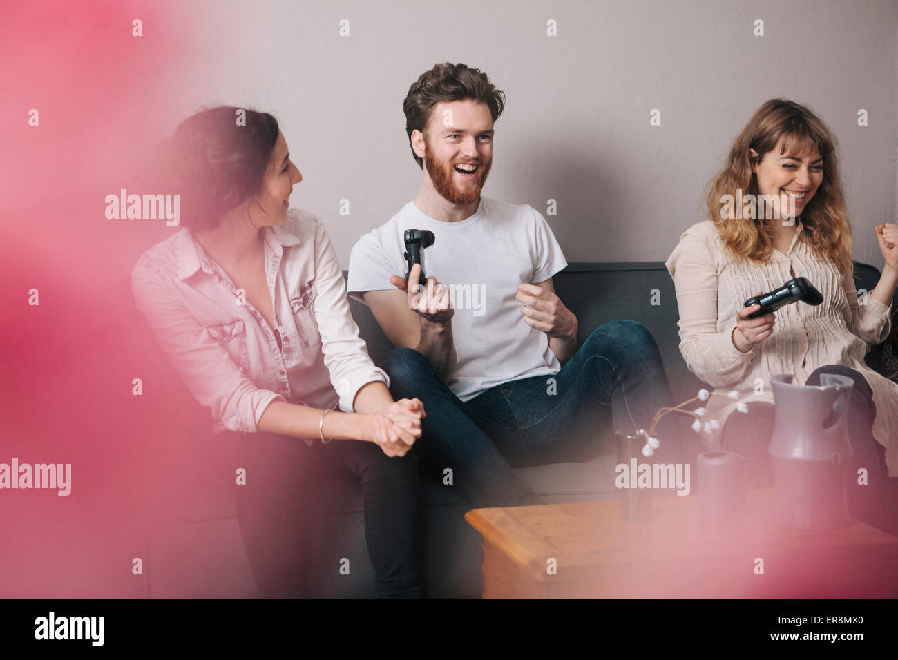 Excited young friends playing video games at home Stock Photo - Alamy