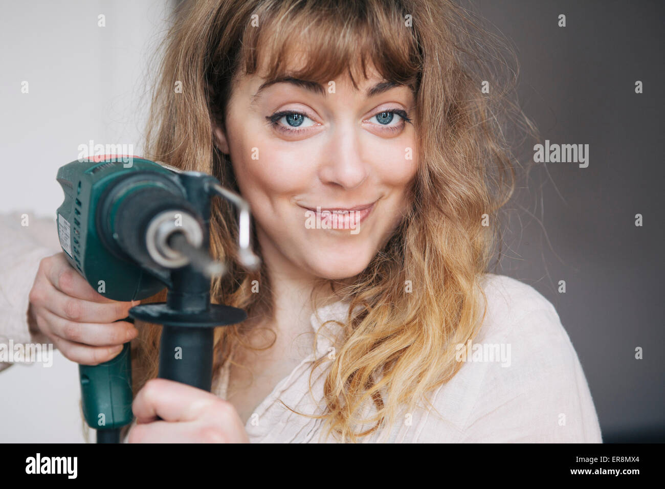 Portrait of confident young woman holding power drill at home Stock ...