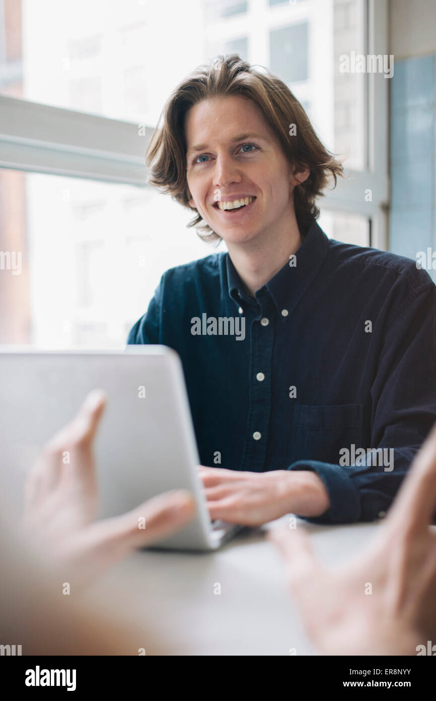 Smiling young man using laptop in living room Stock Photo - Alamy