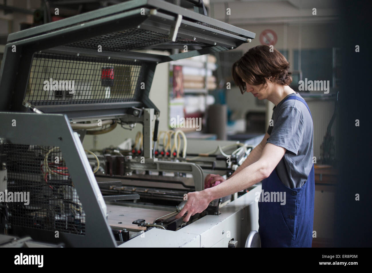 Side view of young manual worker oiling machine in factory Stock Photo ...