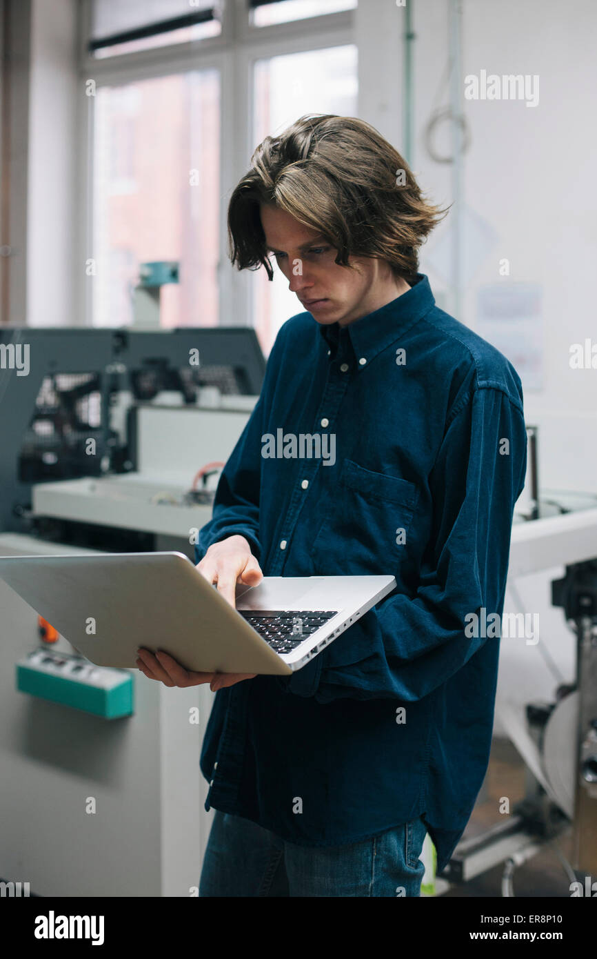 Young male technician using laptop in factory Stock Photo - Alamy