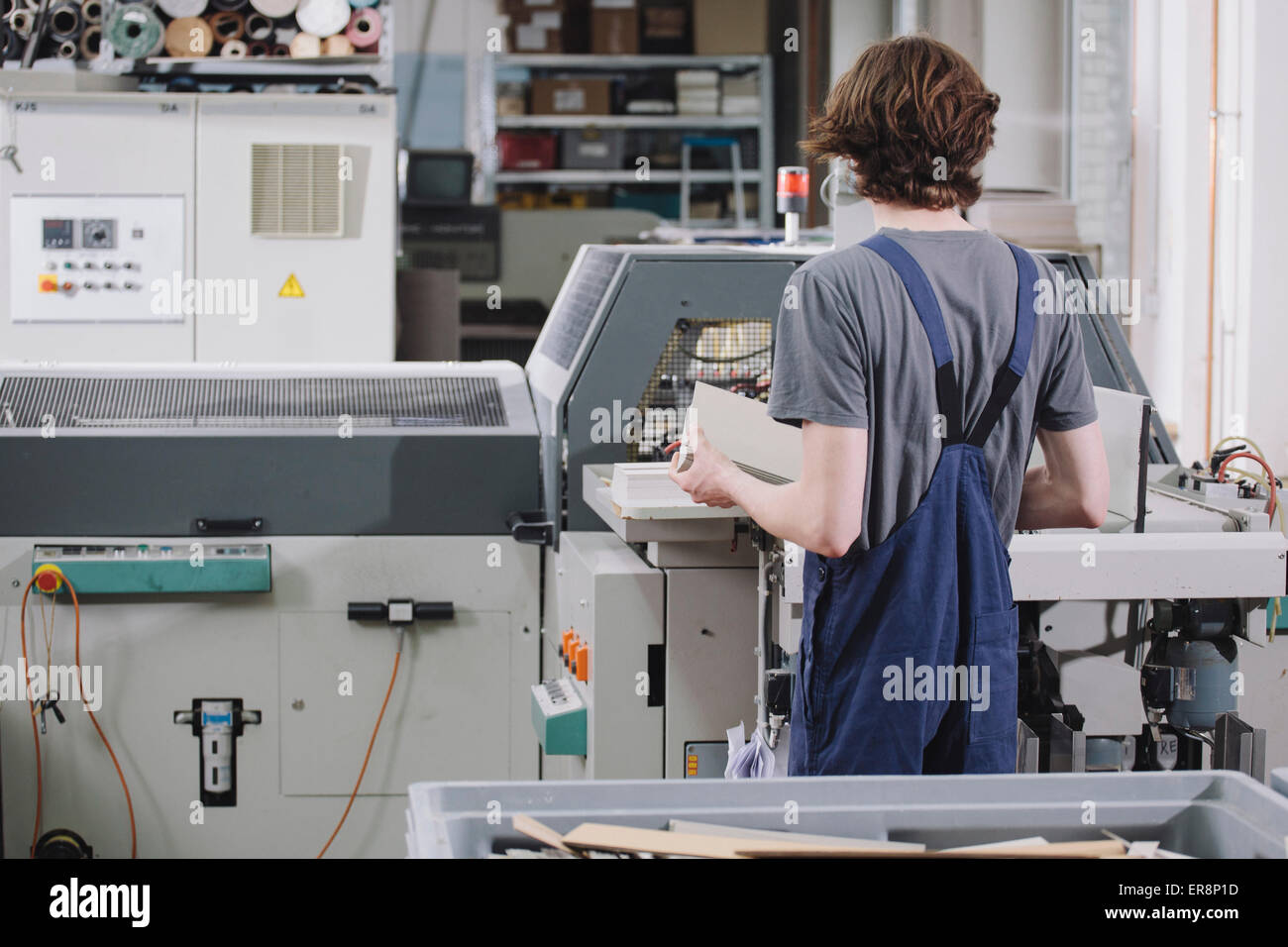 Rear view of young male worker operating machine in factory Stock Photo ...