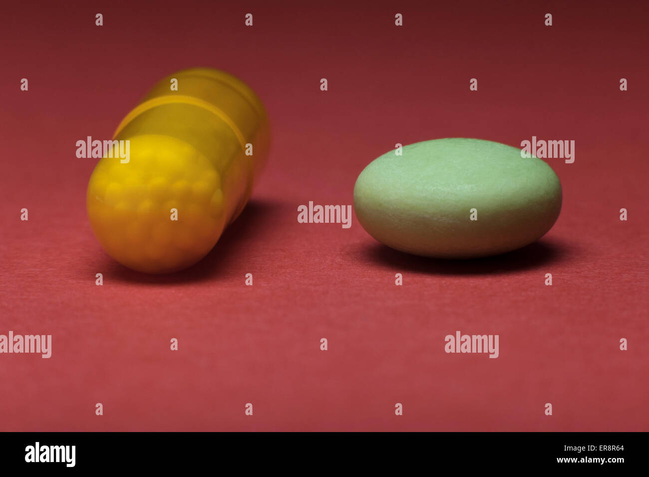 Green Pill and yellow medicine capsule on red background Stock Photo ...