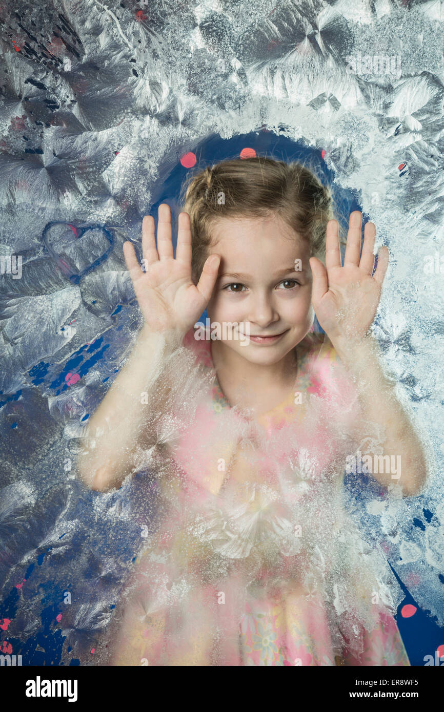 Cute girl looking through frozen glass Stock Photo - Alamy
