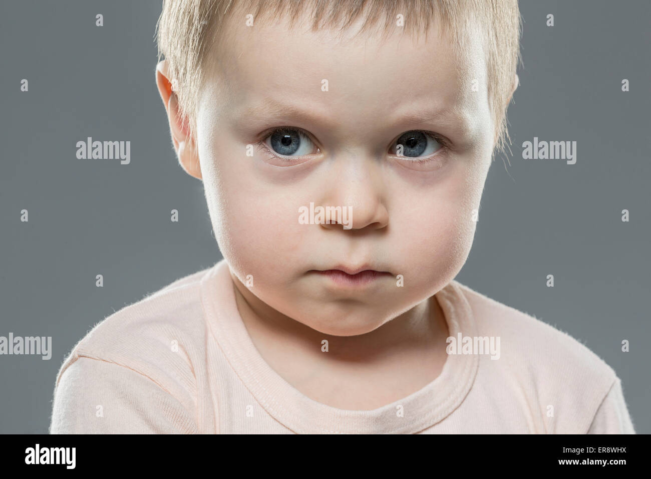 Angry boy looking away against gray background Stock Photo - Alamy