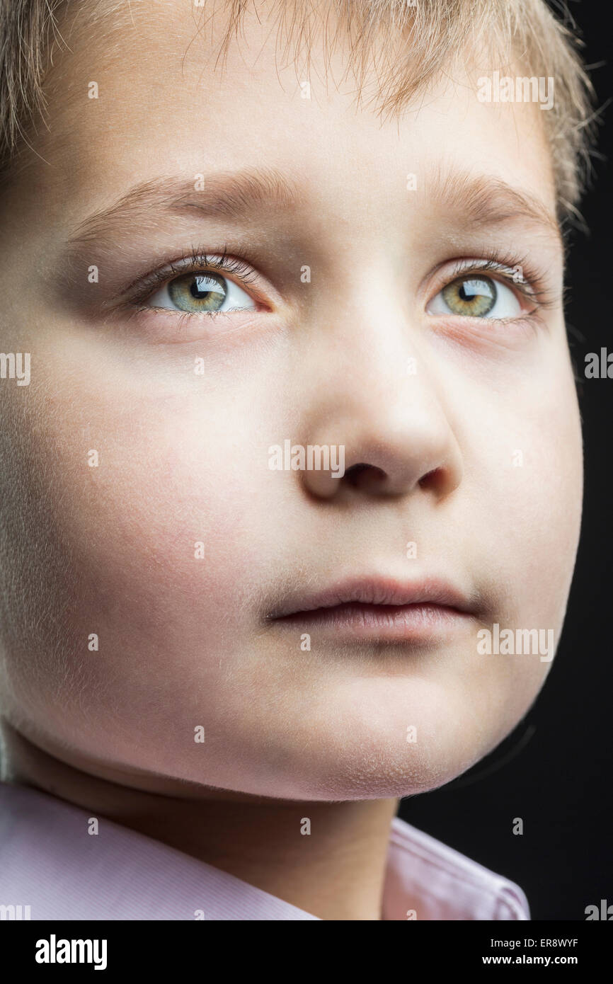 Close-up of thoughtful boy looking away against black background Stock ...