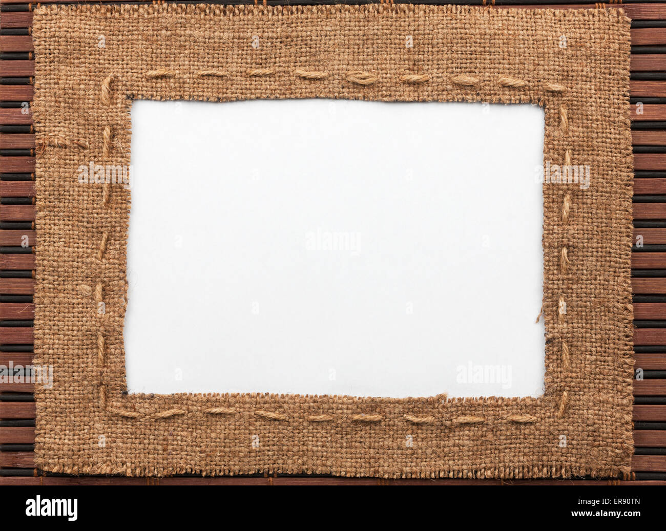 Frame made of burlap with white background lying on a bamboo mat, with ...