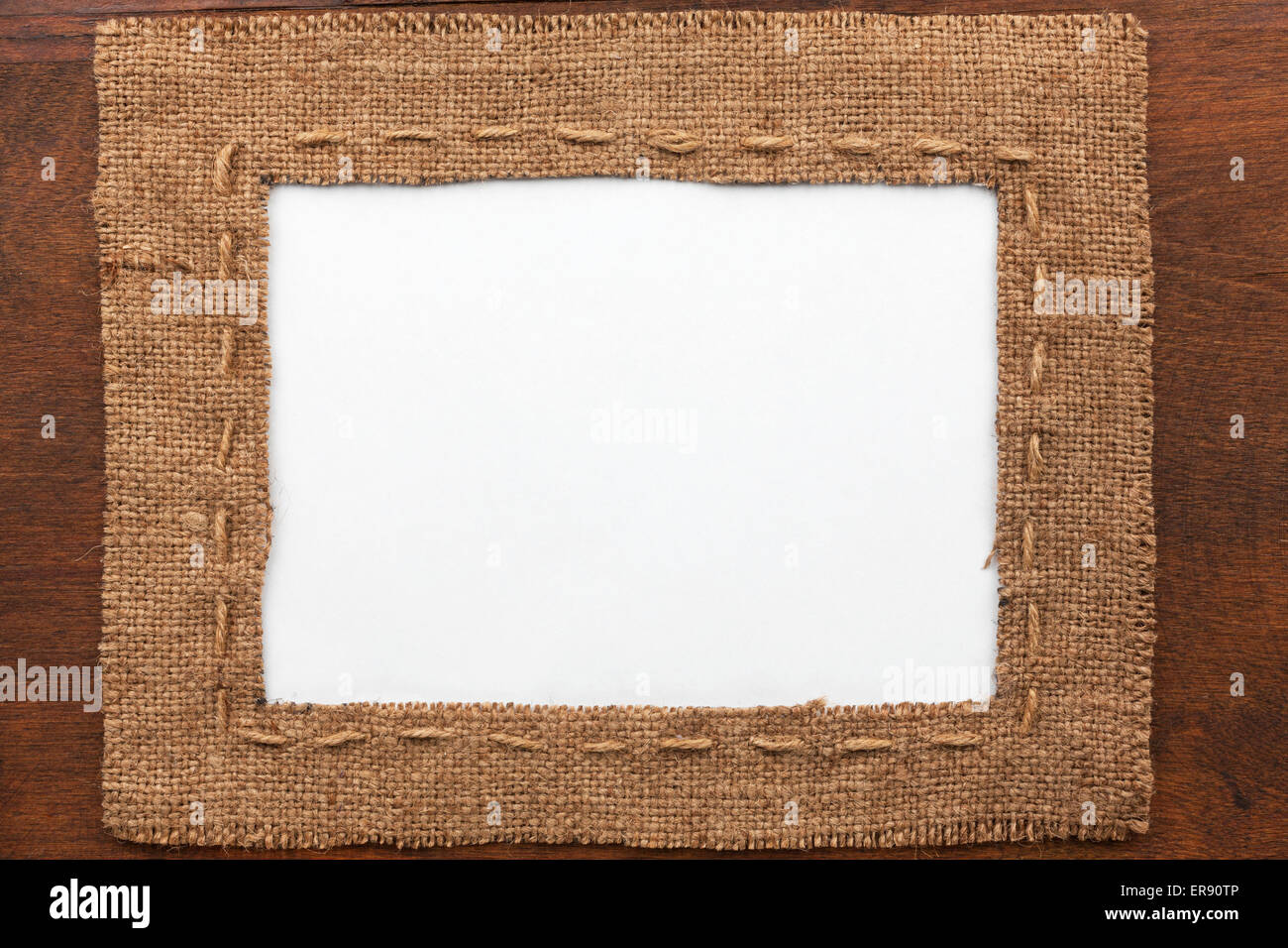 Frame made of burlap with white background lying on a wooden surface ...