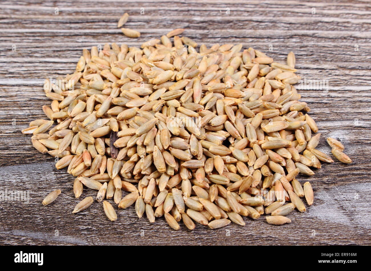 Heap of organic whole rye grain lying on wooden background Stock Photo ...