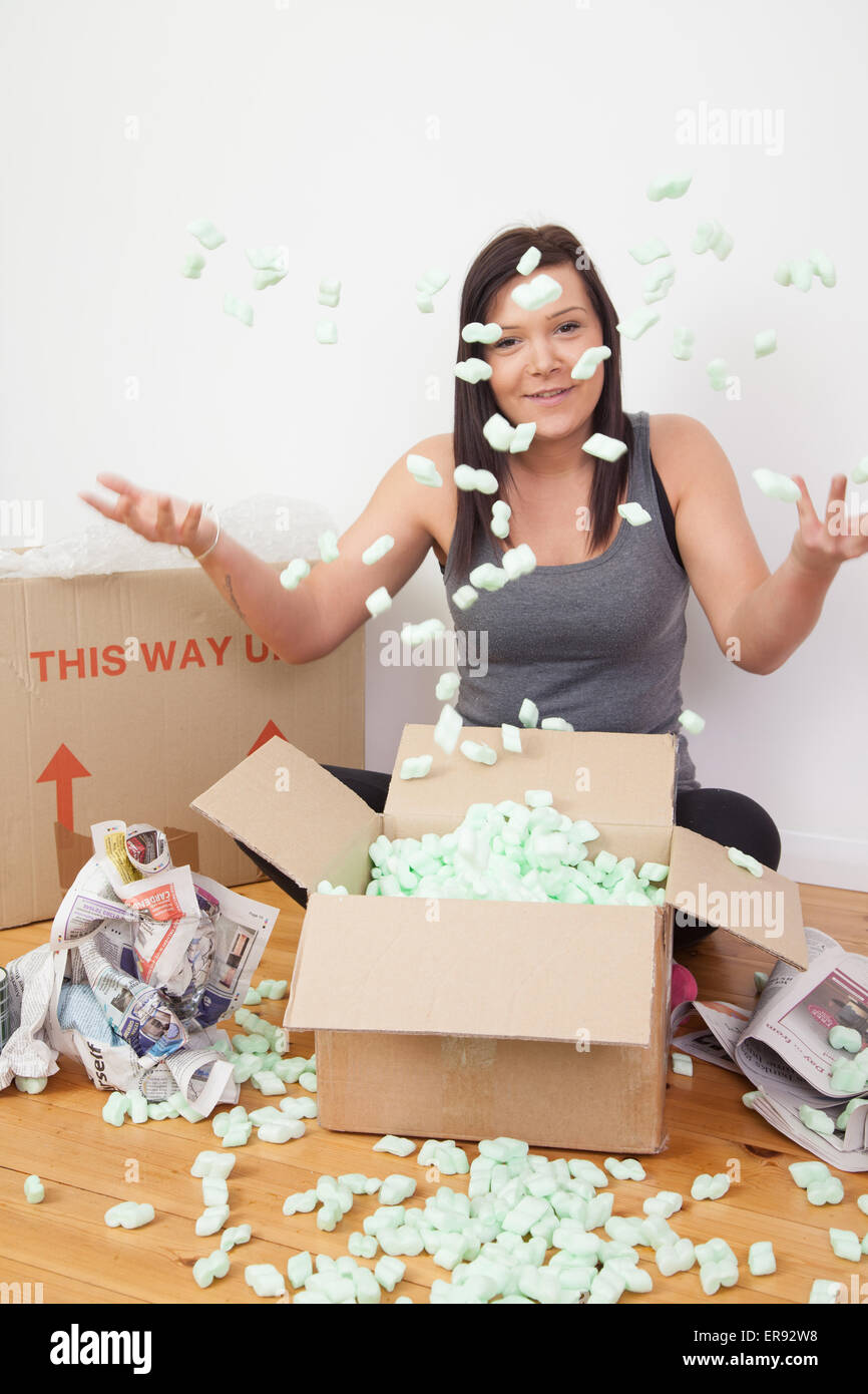 Woman sitting on the floor throwing packing material in the air Stock ...
