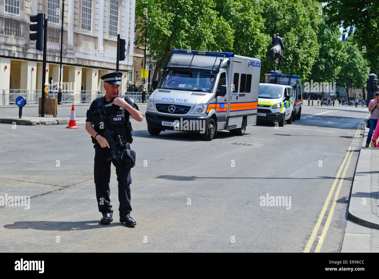 An armed security officer speaking on his radio with two police ...