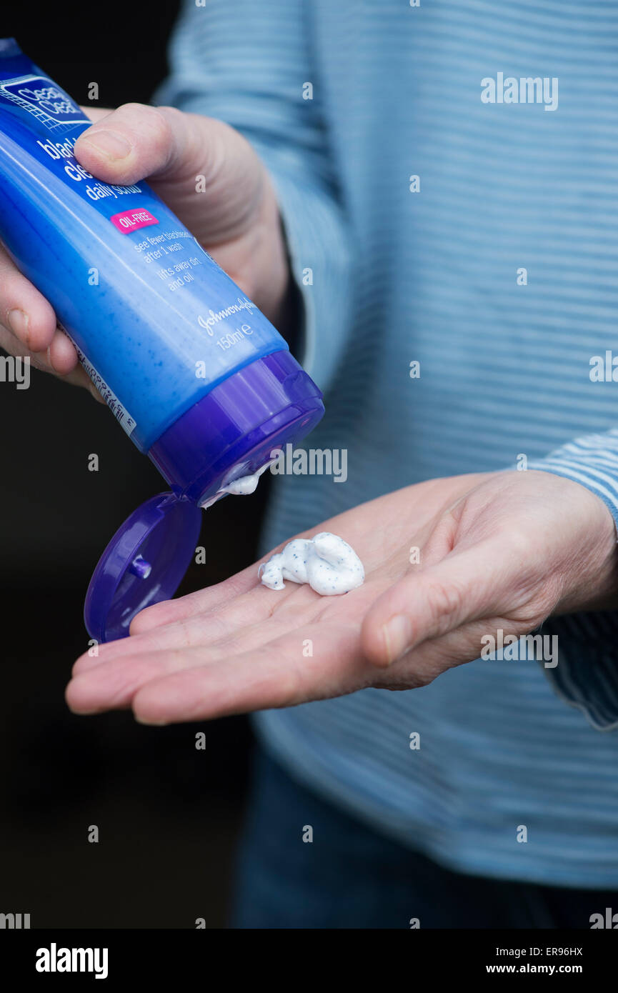 Womans hand holding a facial scrub product with Plastic microbeads ...
