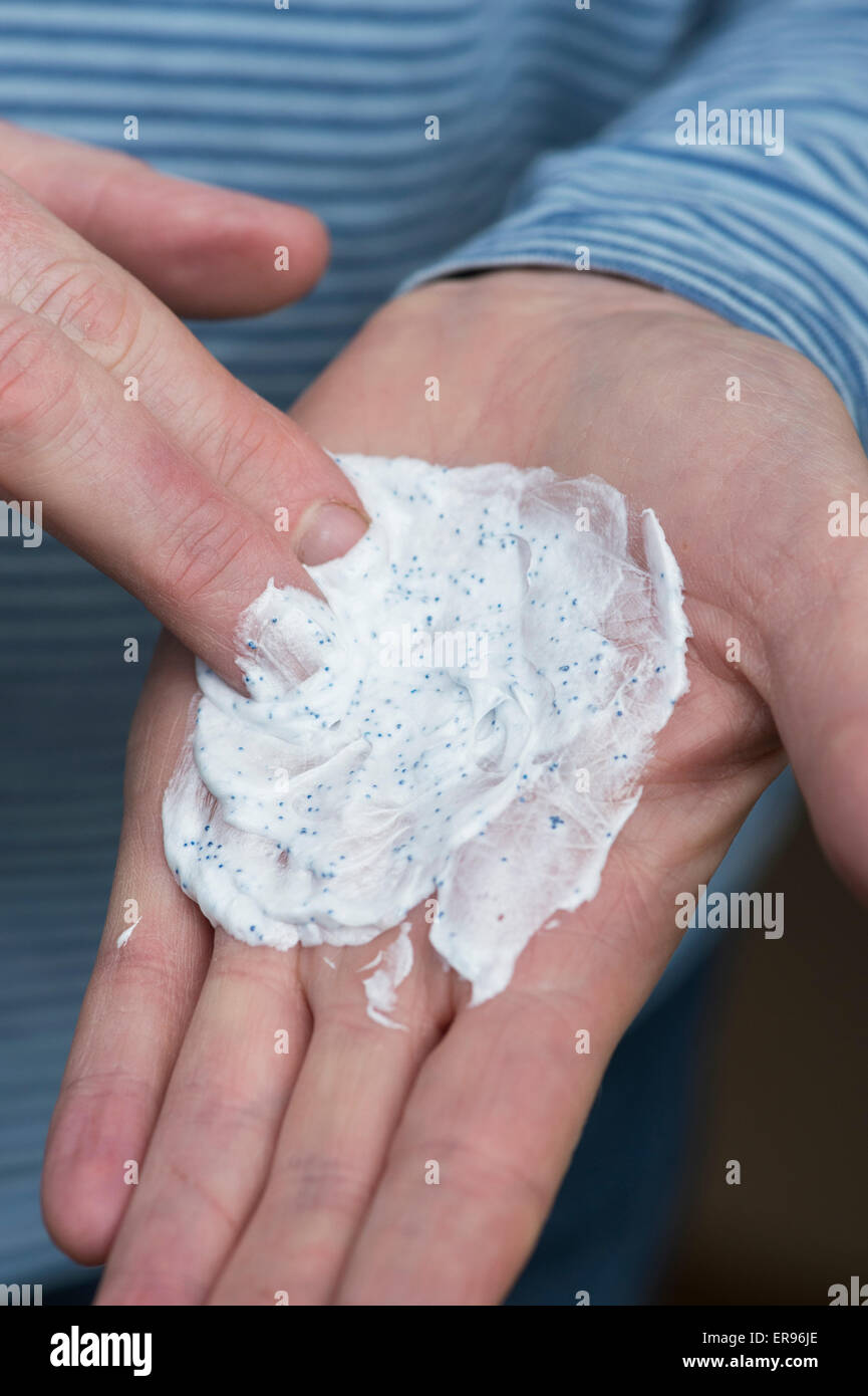 Womans hand holding a facial scrub product with Plastic microbeads ...