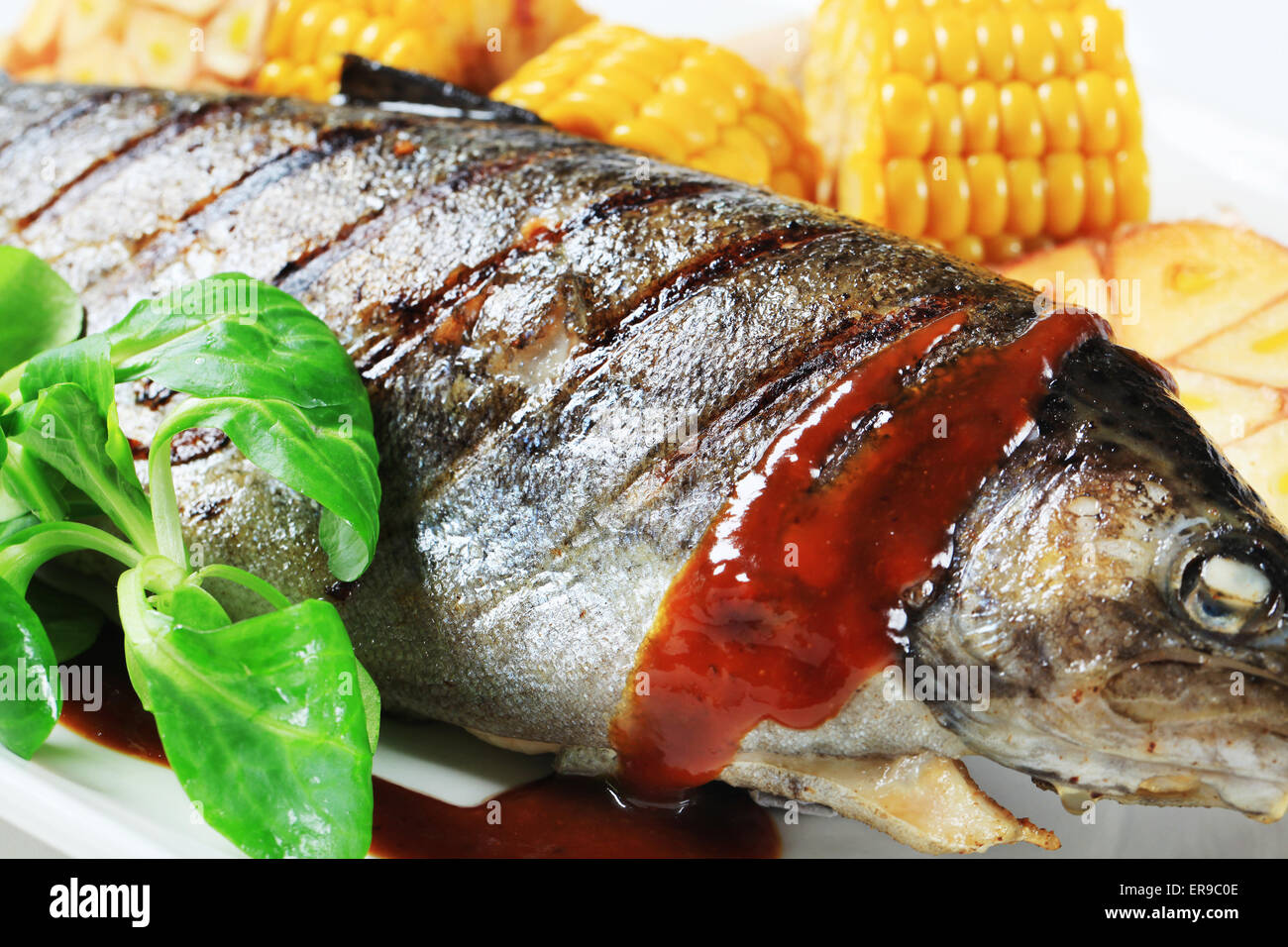 Grilled trout with sweet corn and brown sauce Stock Photo - Alamy