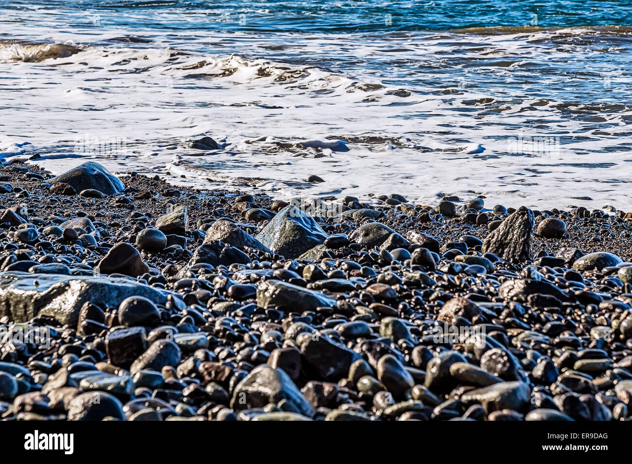 Stones and water of ocean with waves on the beach coast or shore of ...