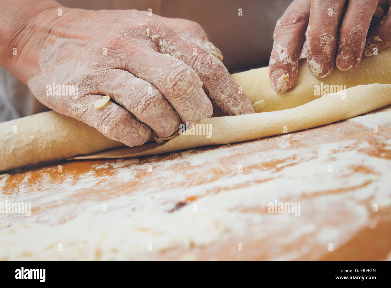 Close up photo of baker kneading dough with a rolling pin. Retro styled ...