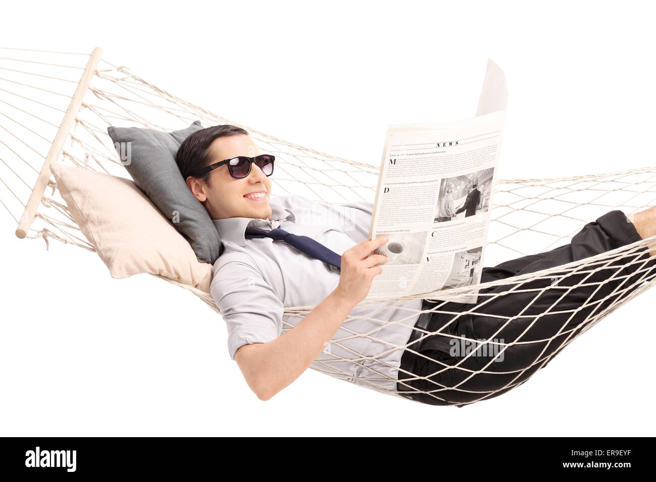 Relaxed young man reading a newspaper and lying in a hammock isolated ...