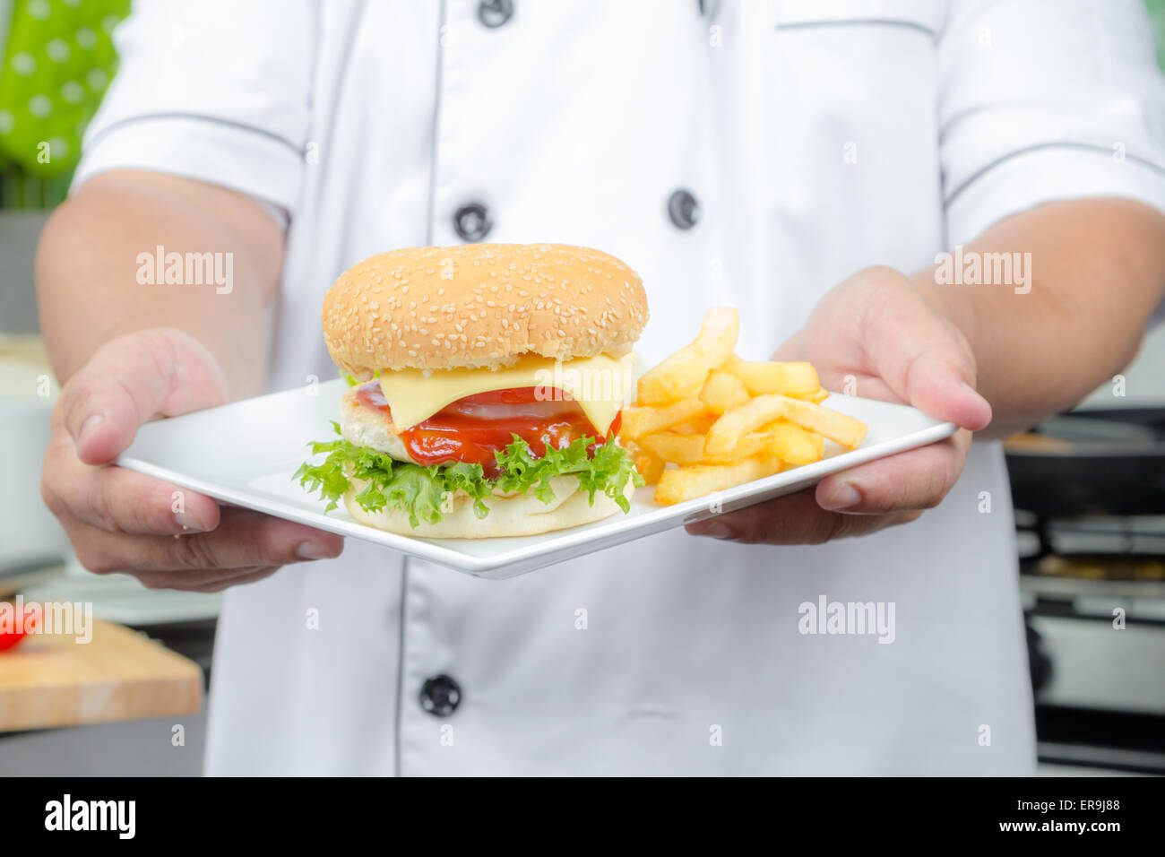chef holding american cheese burger with fresh salad and french fries ...
