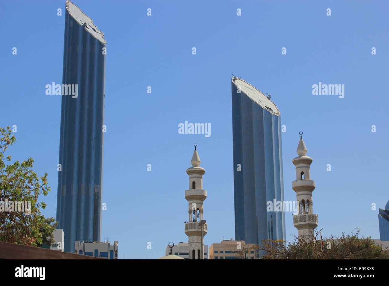 View of a mosque minarets against a backdrop of twin modern skyscrapers ...