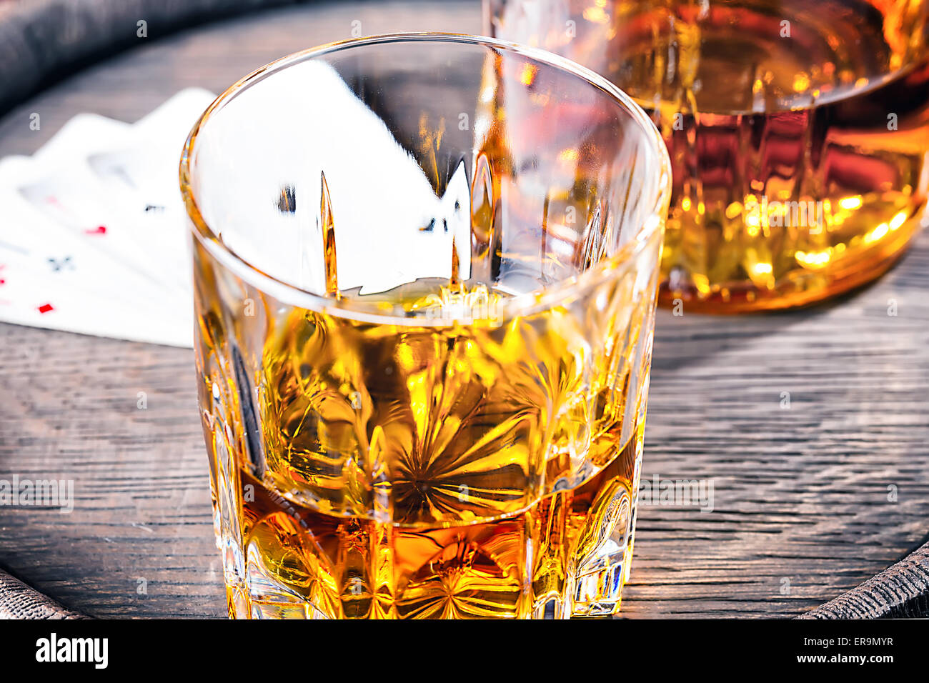 Glass and decanter of brandy and four aces on wooden barrel Stock Photo ...