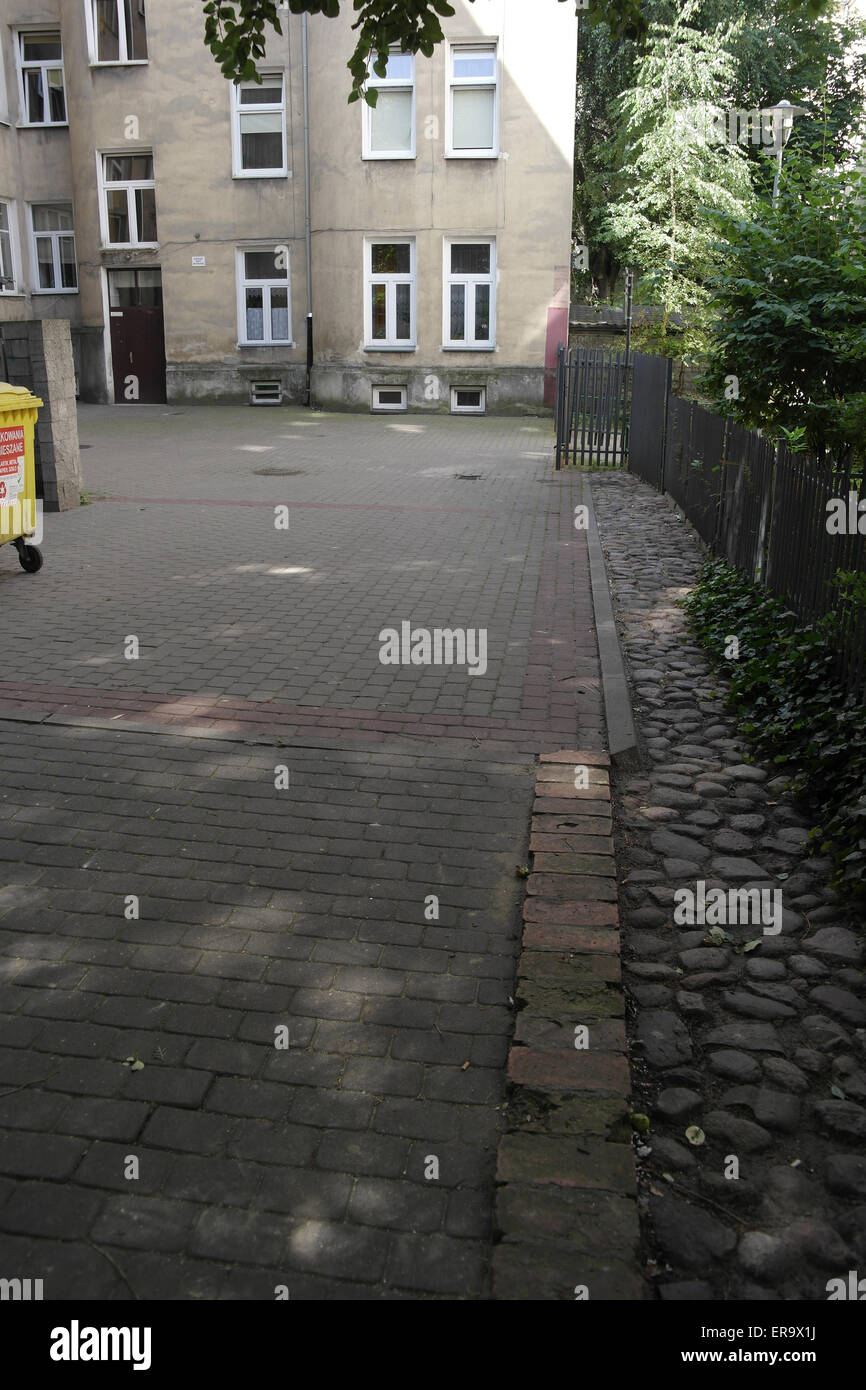 Red brick foundations Warsaw Ghetto Wall crossing courtyard with yellow ...