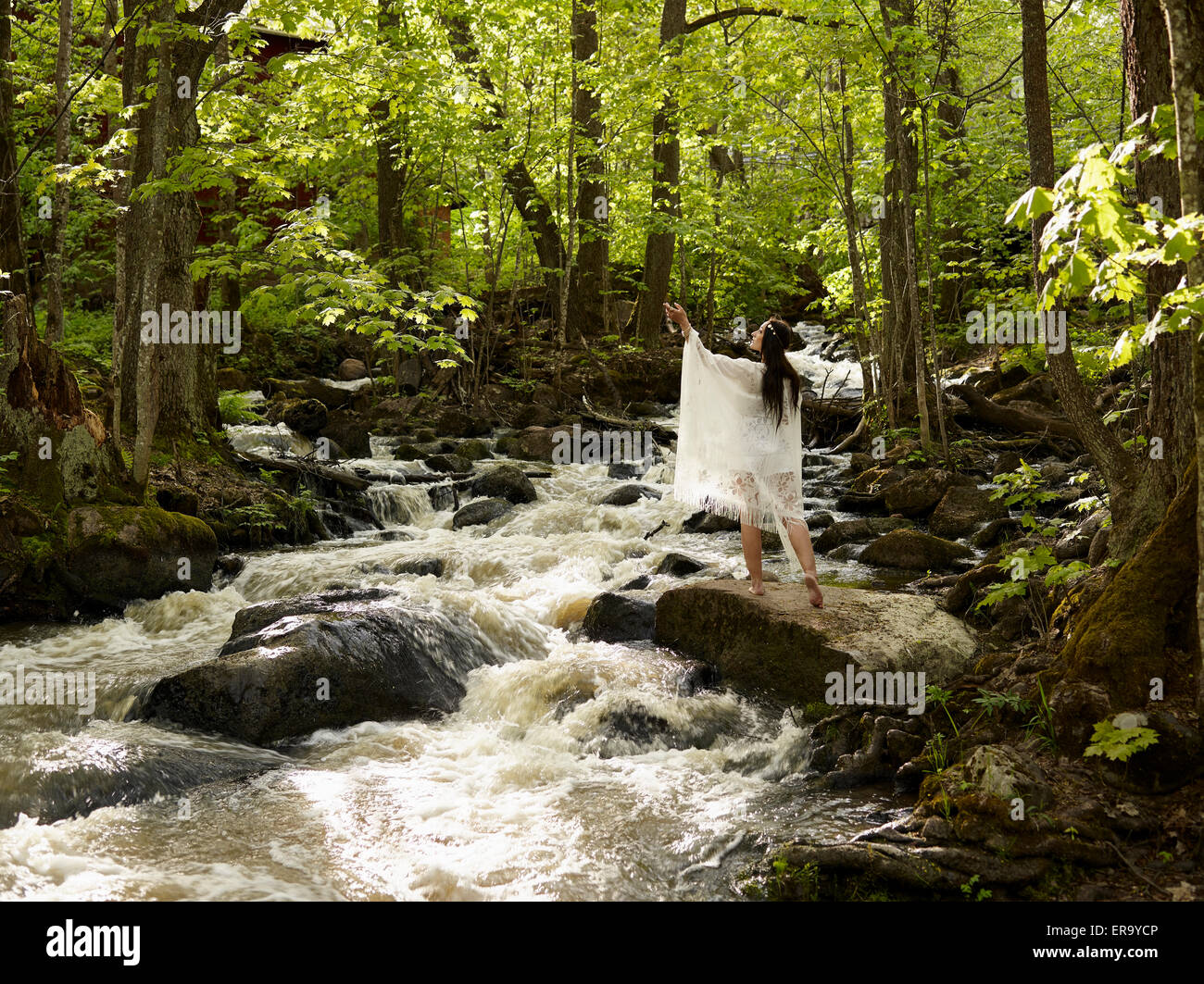 Beautiful brunette woman alone on a river, white dress Stock Photo - Alamy