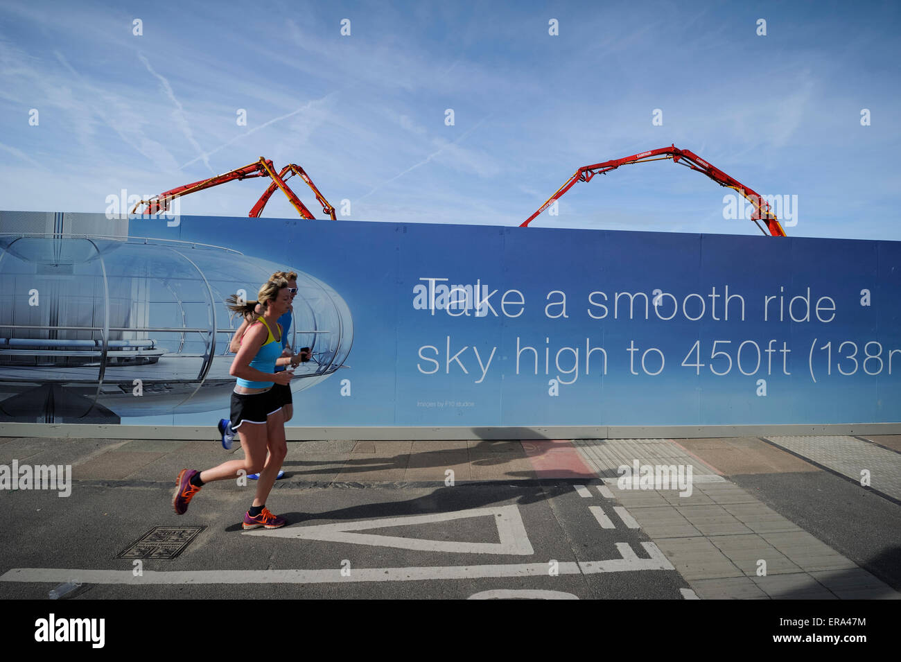 Two runners pass in in front of hoarding used to hide the construction ...