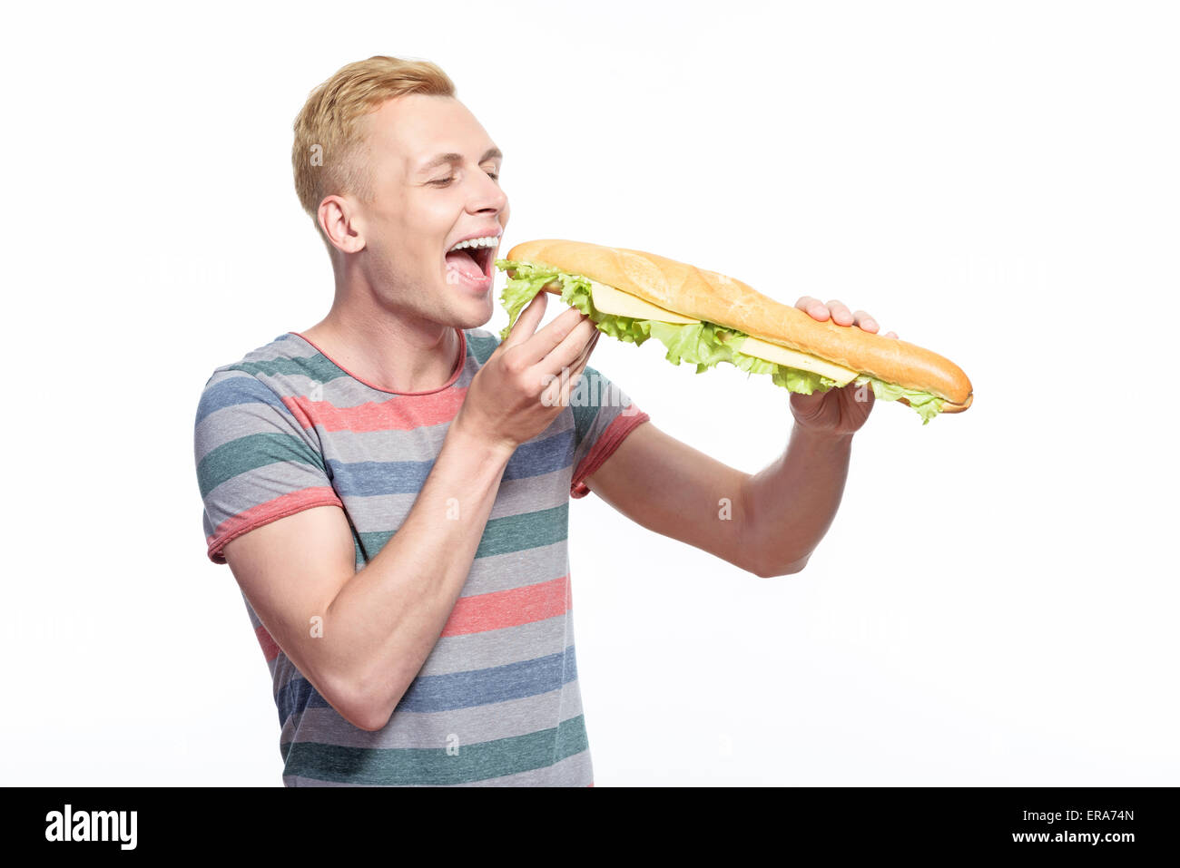 Young smiling man starting to eat long sandwich Stock Photo - Alamy