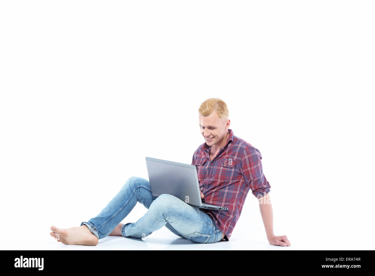 Young man sitting with computer on floor Stock Photo - Alamy