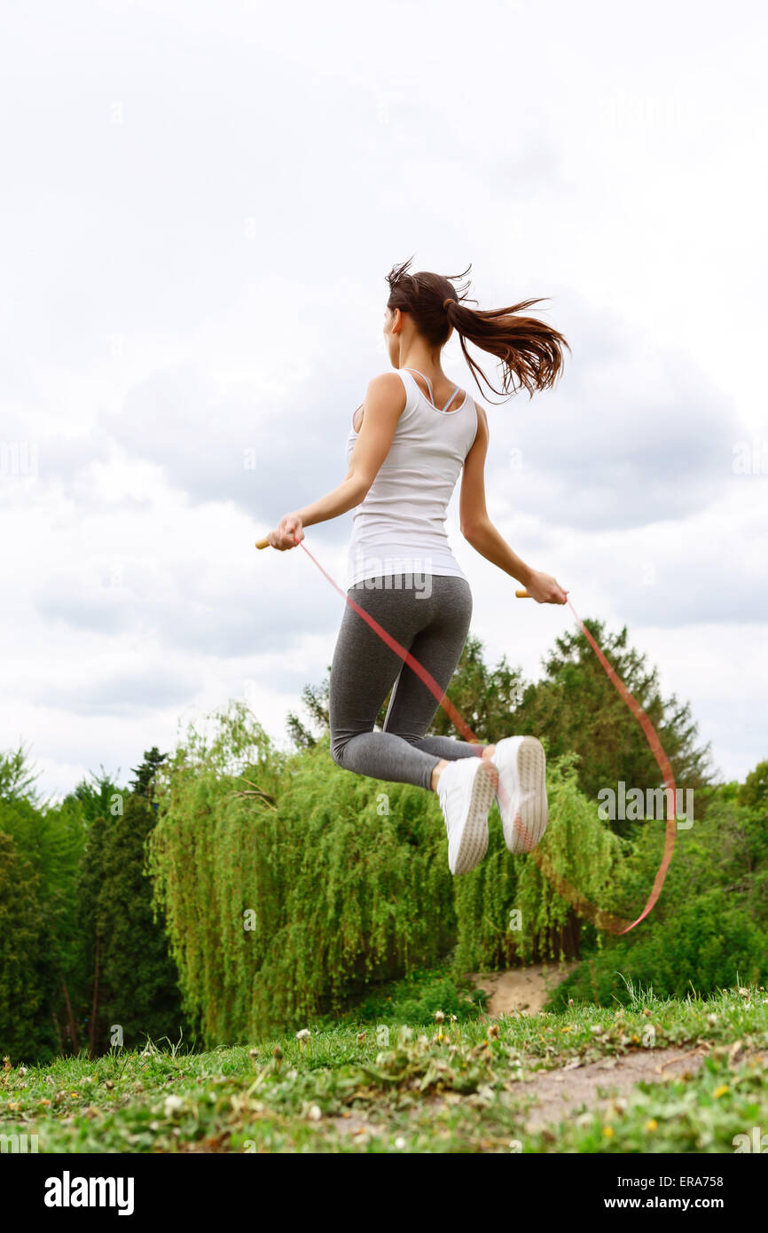 Young slim woman skipping in park Stock Photo - Alamy
