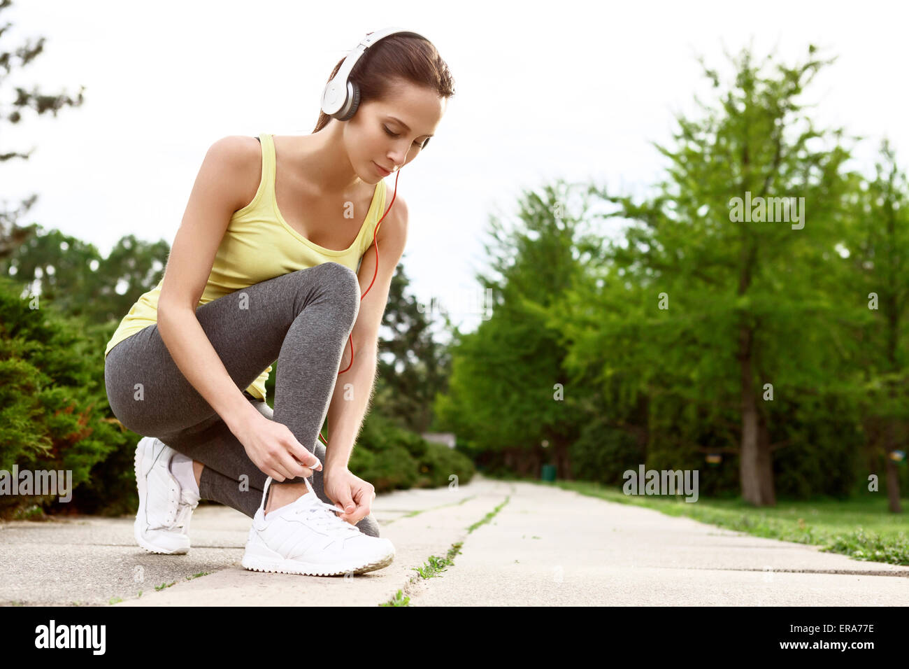 Woman lacing her shoes in park Stock Photo - Alamy