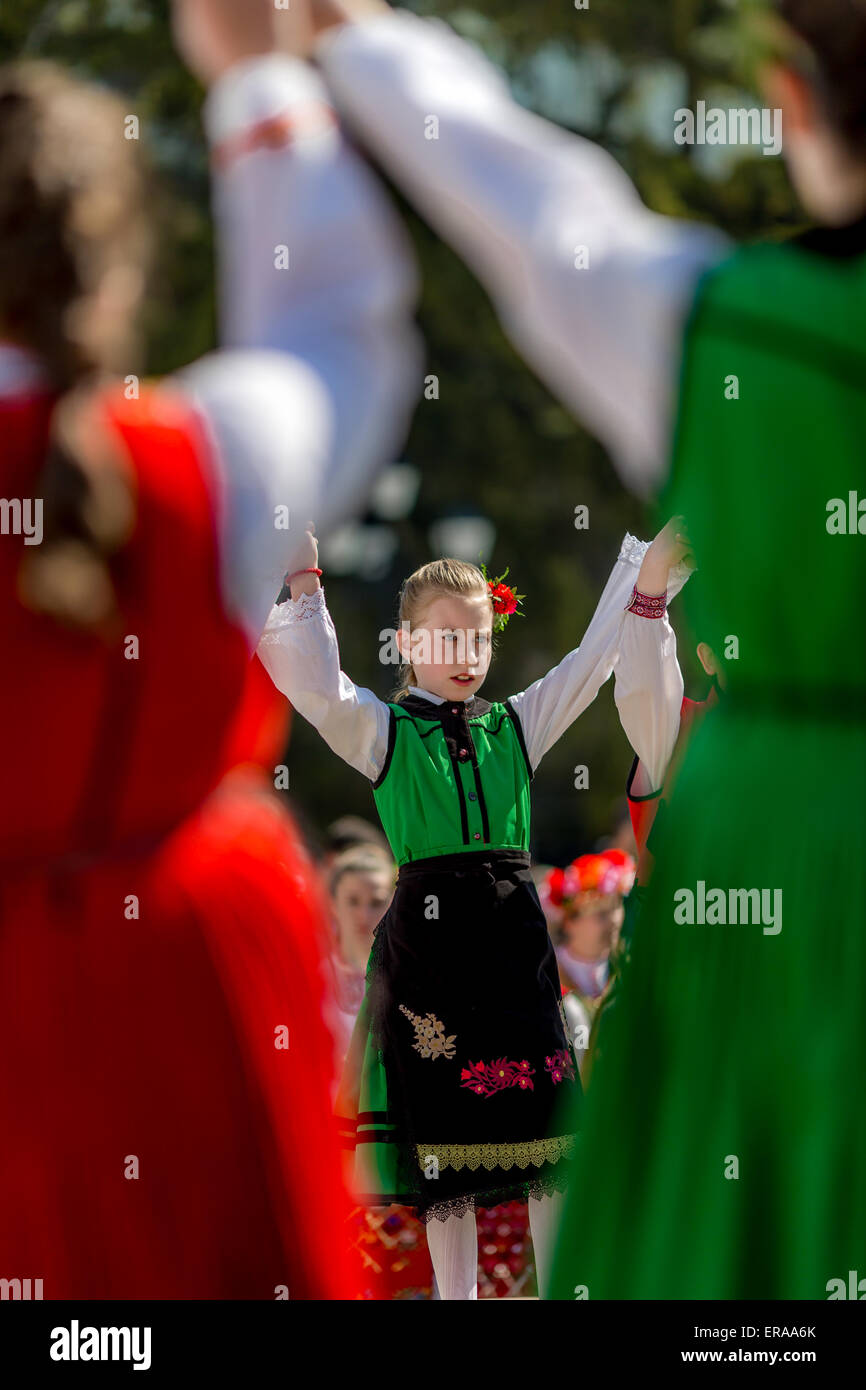A young female Bulgarian folklore dancer raising her hands during a ...
